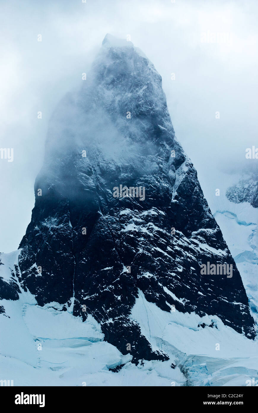 A dark brooding storm descends on a massive jagged mountain peak Stock ...