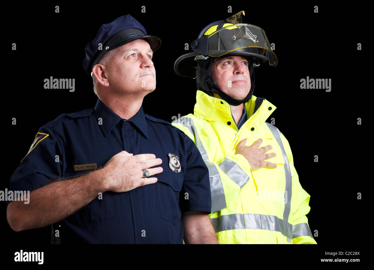Police officer and fire fighter with their hands over their hearts as ...
