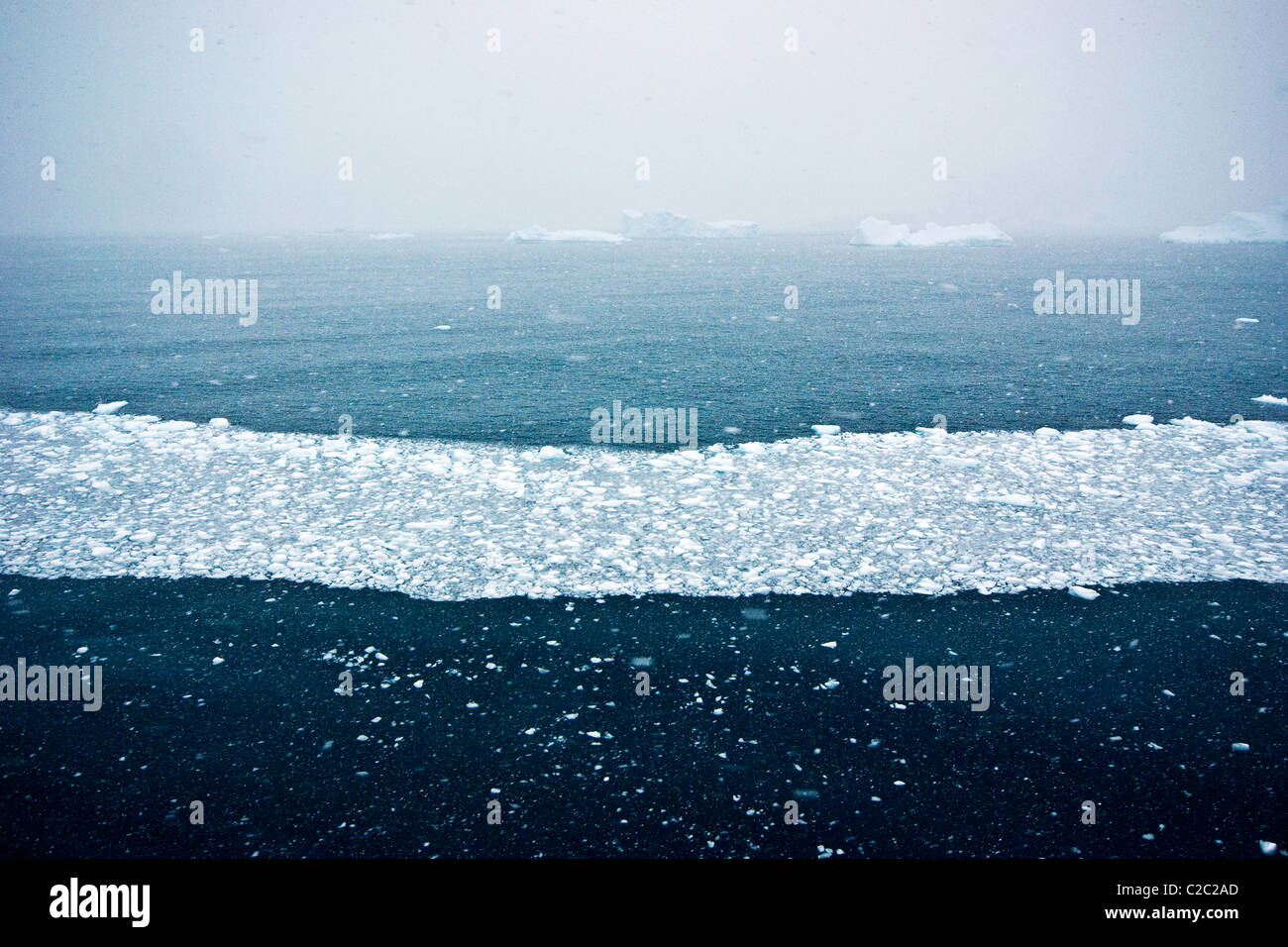 Icebergs float on a sea current in a blizzard beneath a grey sky Stock ...