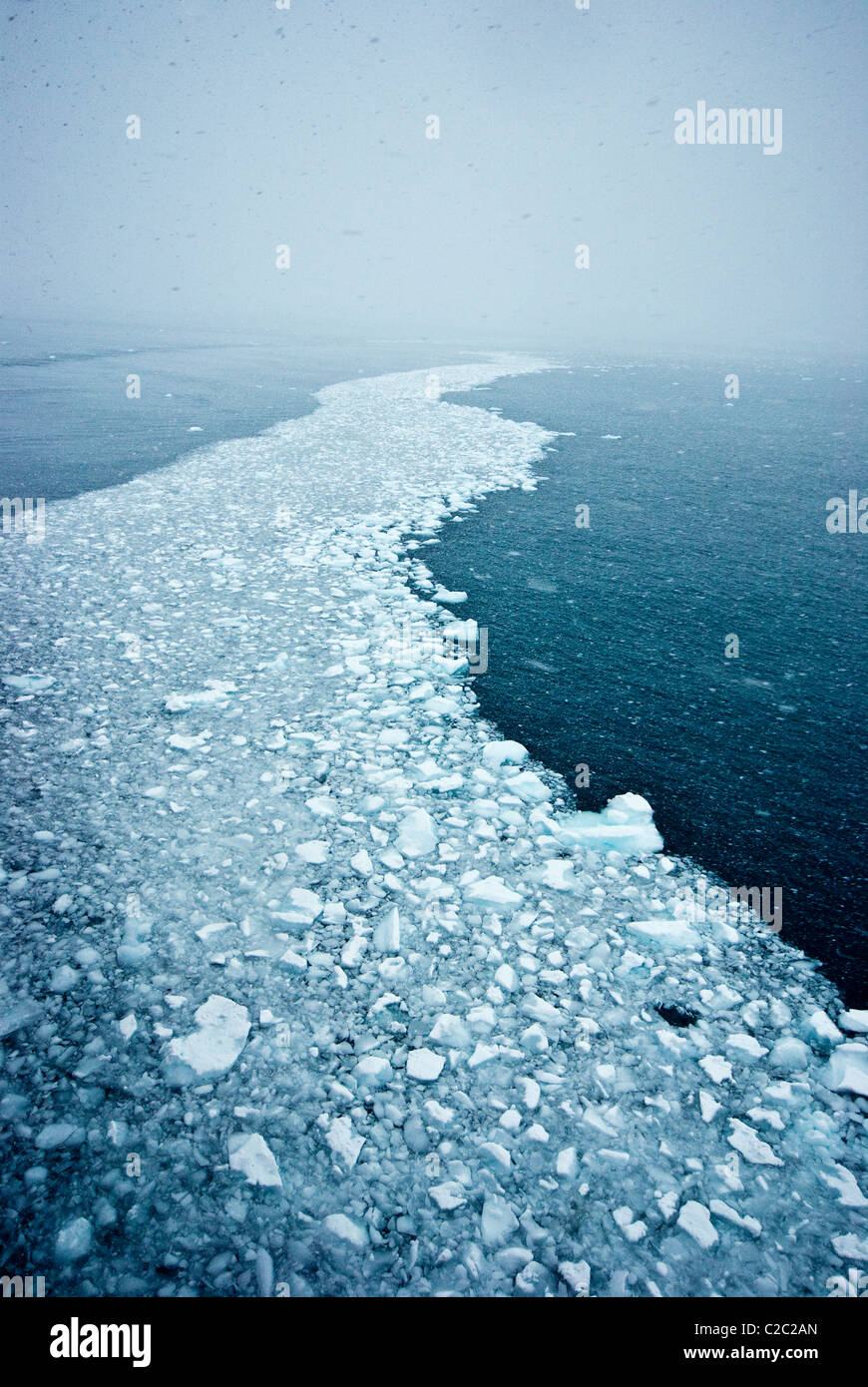 Icebergs float on a sea current in a blizzard beneath a grey sky Stock ...