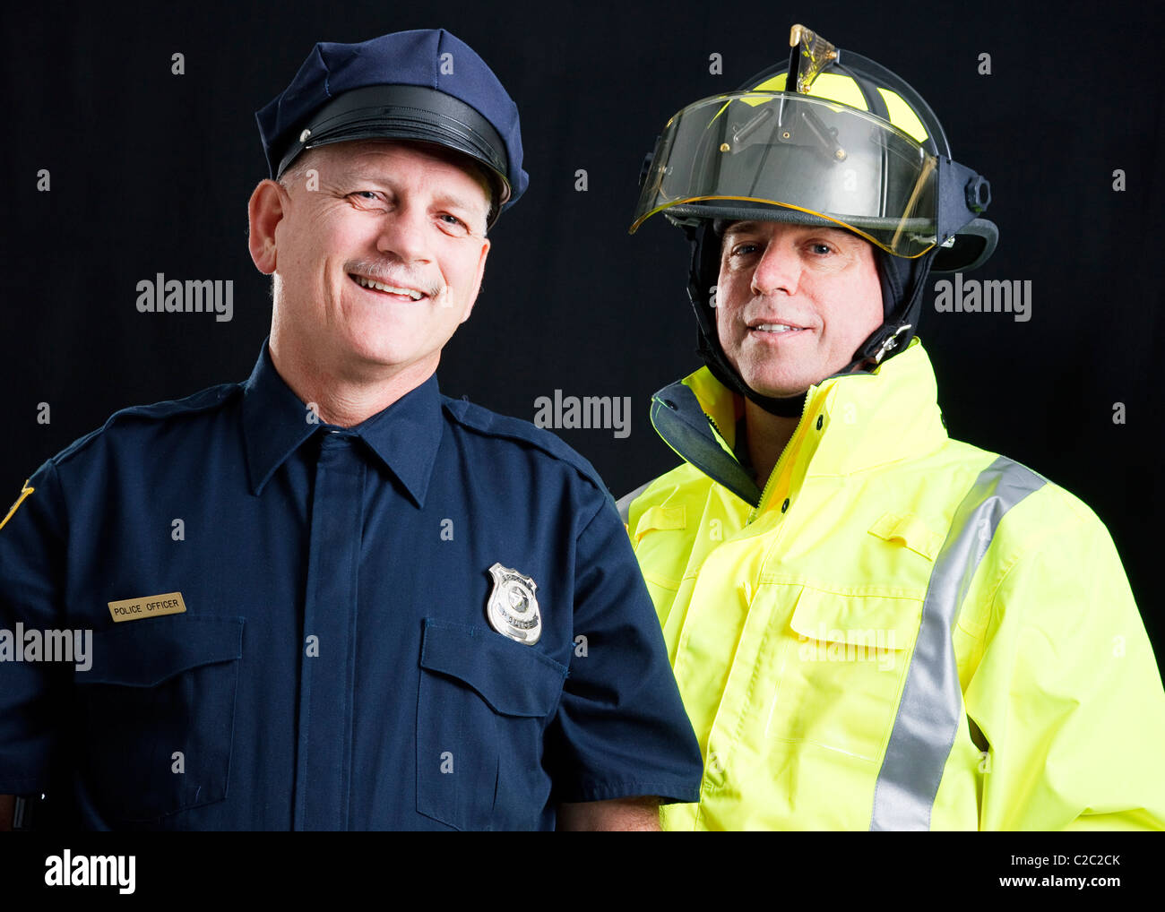 Policeman and fireman both photographed against a black background ...