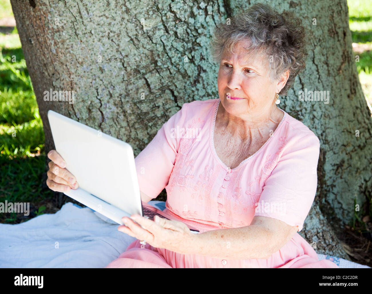 Senior woman trying to use a netbook computer and getting frustrated ...