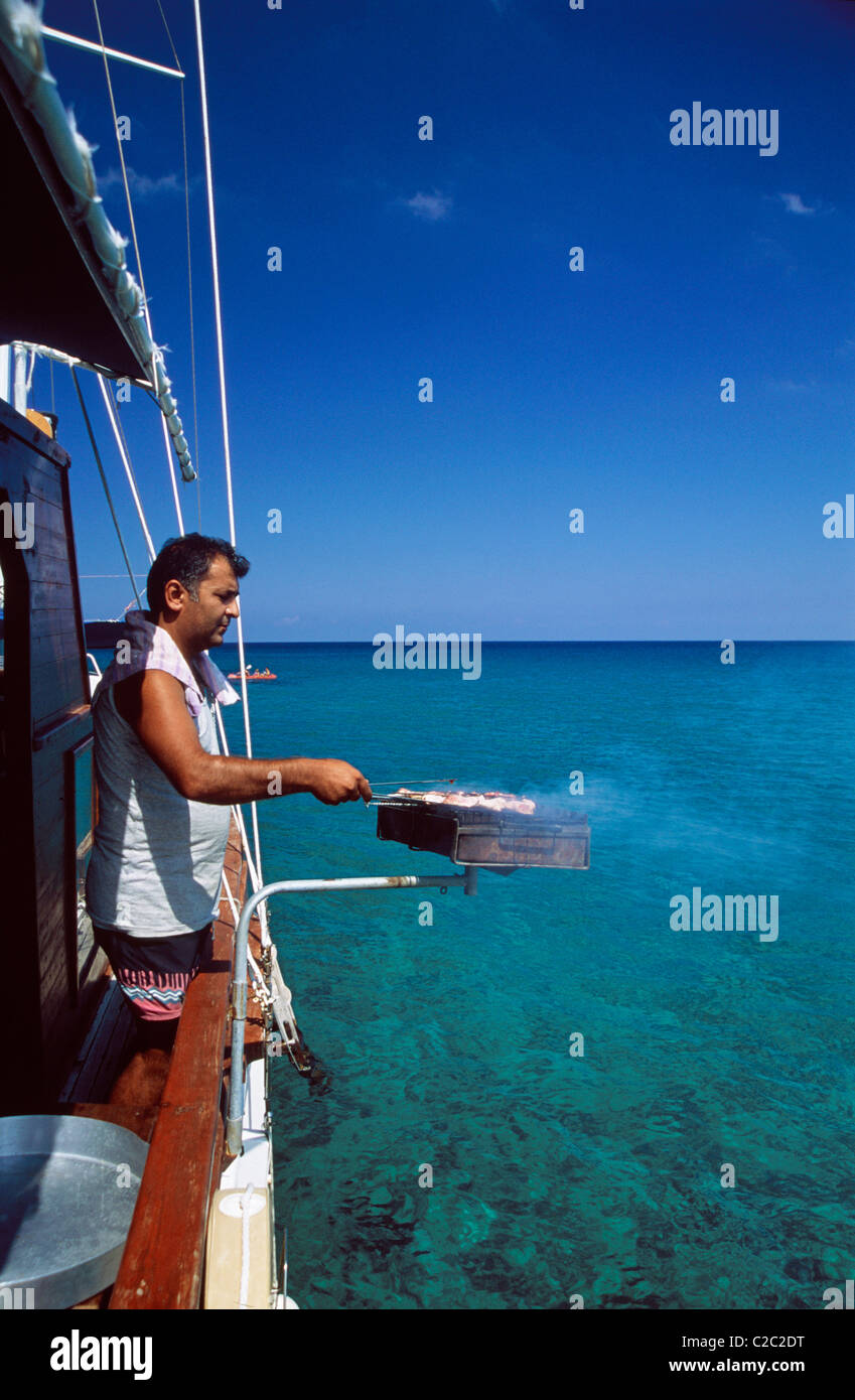 Man cooking fish on barbeque over the side of a boat. Fishing sport ...