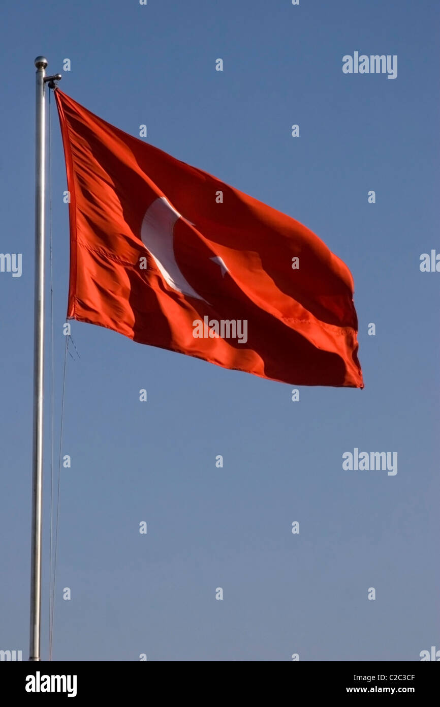 The bright and colorful flag of Turkey is flying under blue sky near ...