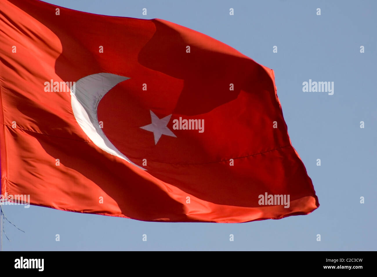 The bright and colorful flag of Turkey is flying under blue sky near ...