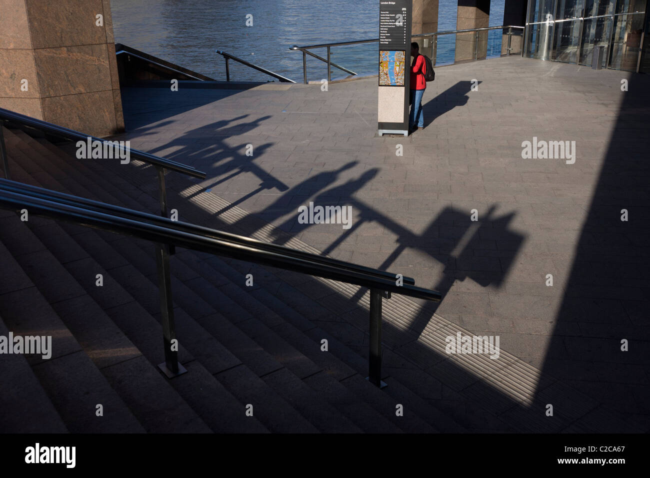 Man in red inspects a city map amid shadows and modernist architecture ...