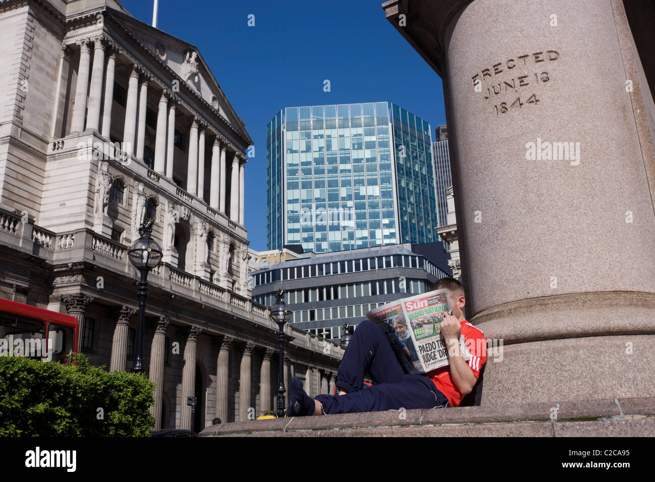A Sun newspaper reader below a statue at Bank Triangle, with the Bank ...