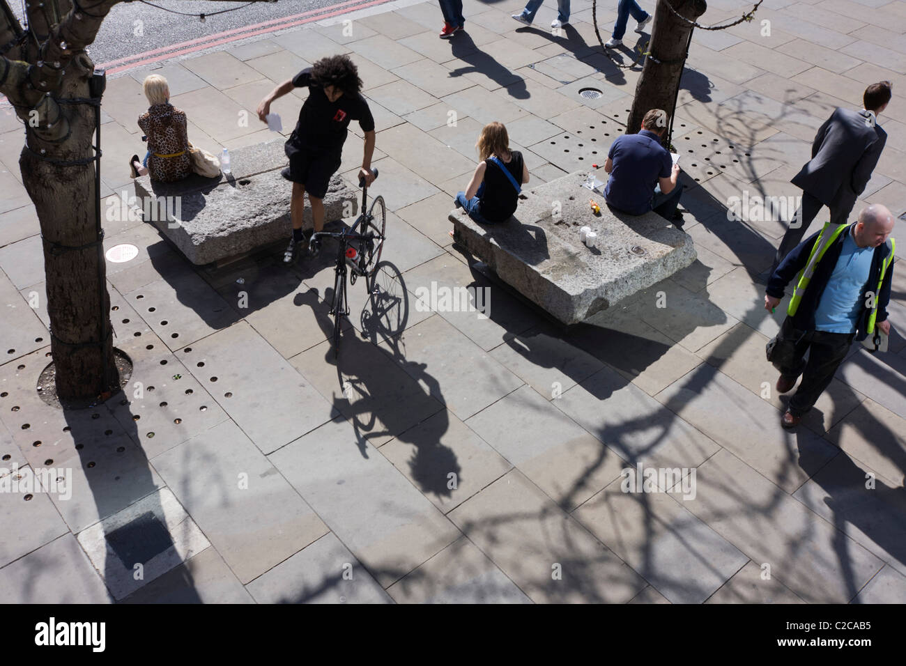 A cyclist jumps over a stone bench past pedestrians and passers-by ...