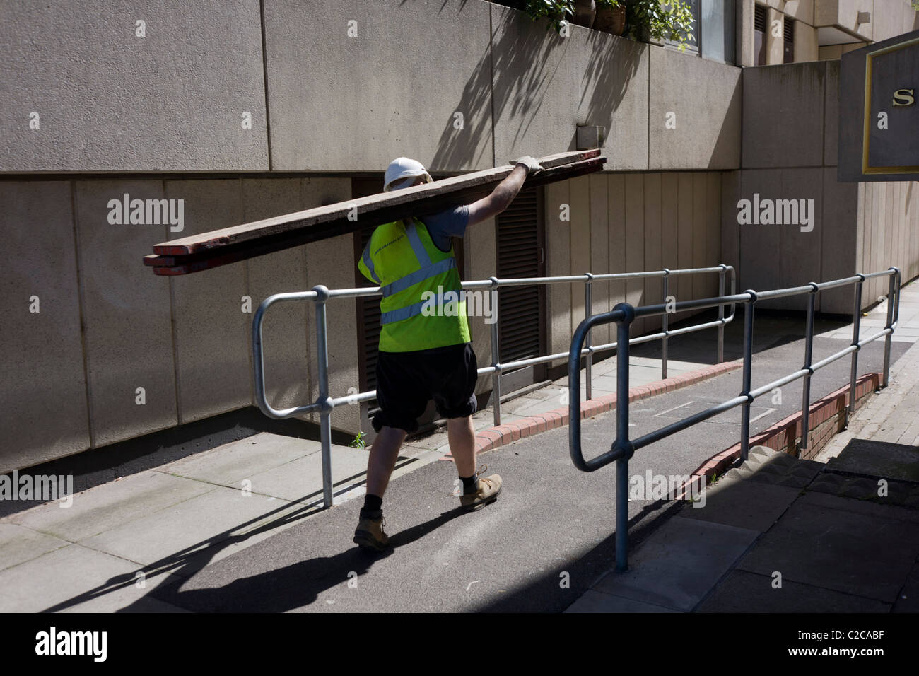 A workman carries a ladder over a ramp and along an alleyway Stock ...