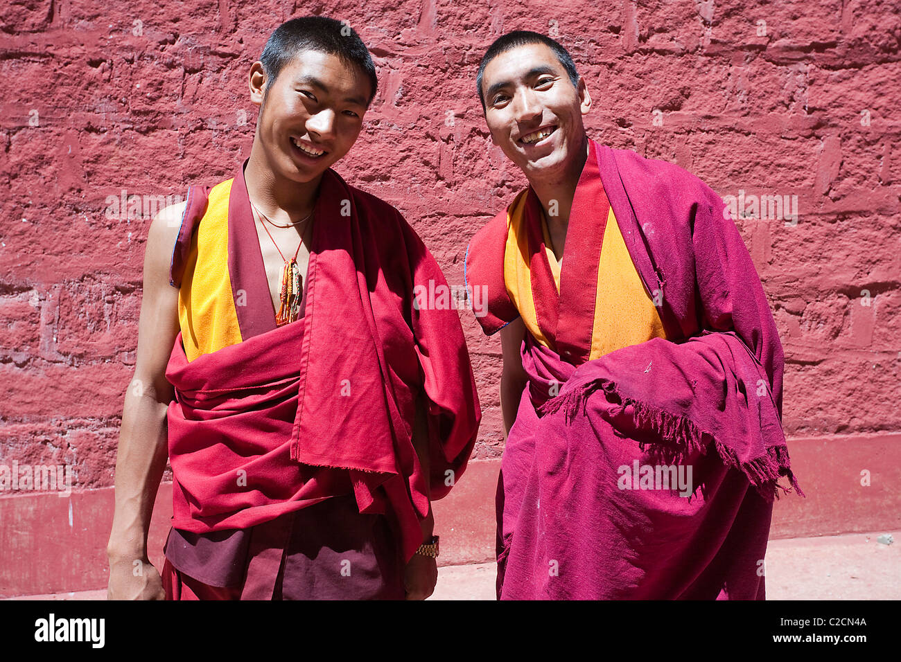 two young buddhist monks dressed in robes smile to camera in front of a ...