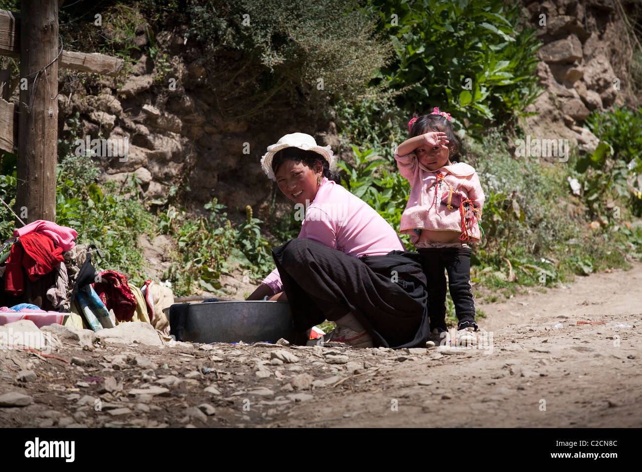 A local tibetan woman washes her clothes in a small ravine, as her ...