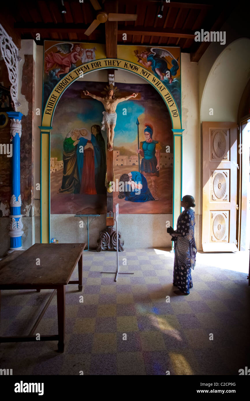 a lady looks at a colourful depiction of Jesus on the cross at the ...