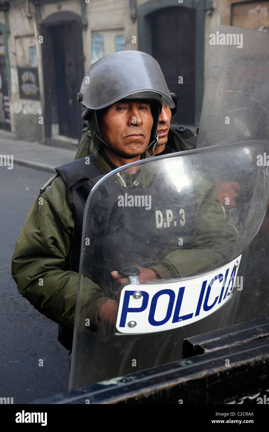 Riot policeman with stern expression standing behind security barrier ...