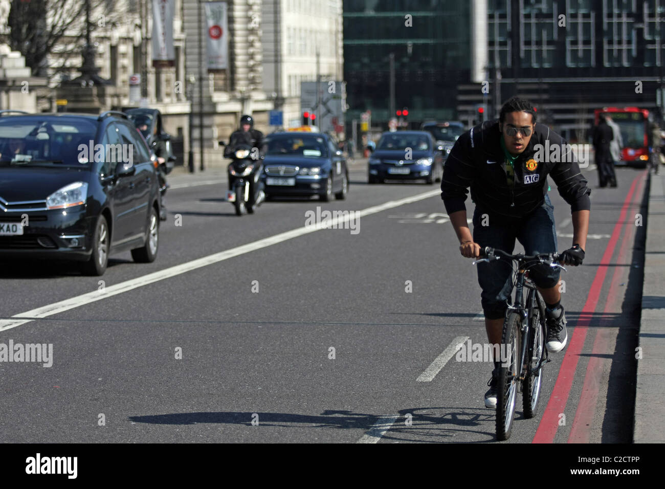 A male cyclist standing up to cycle in sunshine in London, England ...