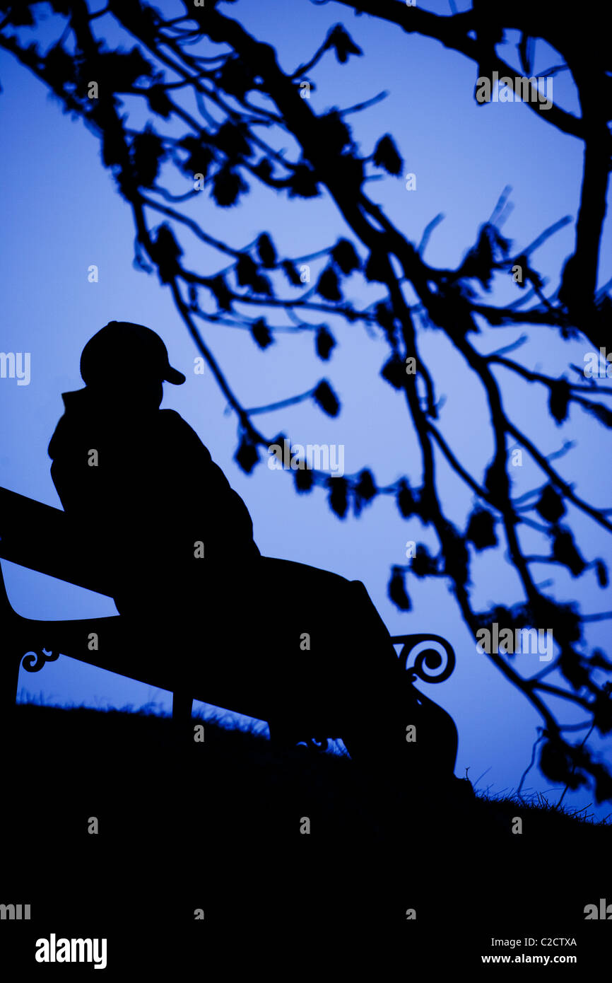 A person sitting alone on a bench Stock Photo - Alamy