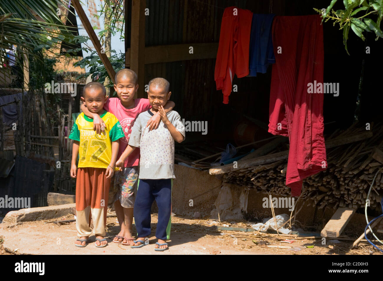 Three young Asian boys living in poverty are standing together at a ...