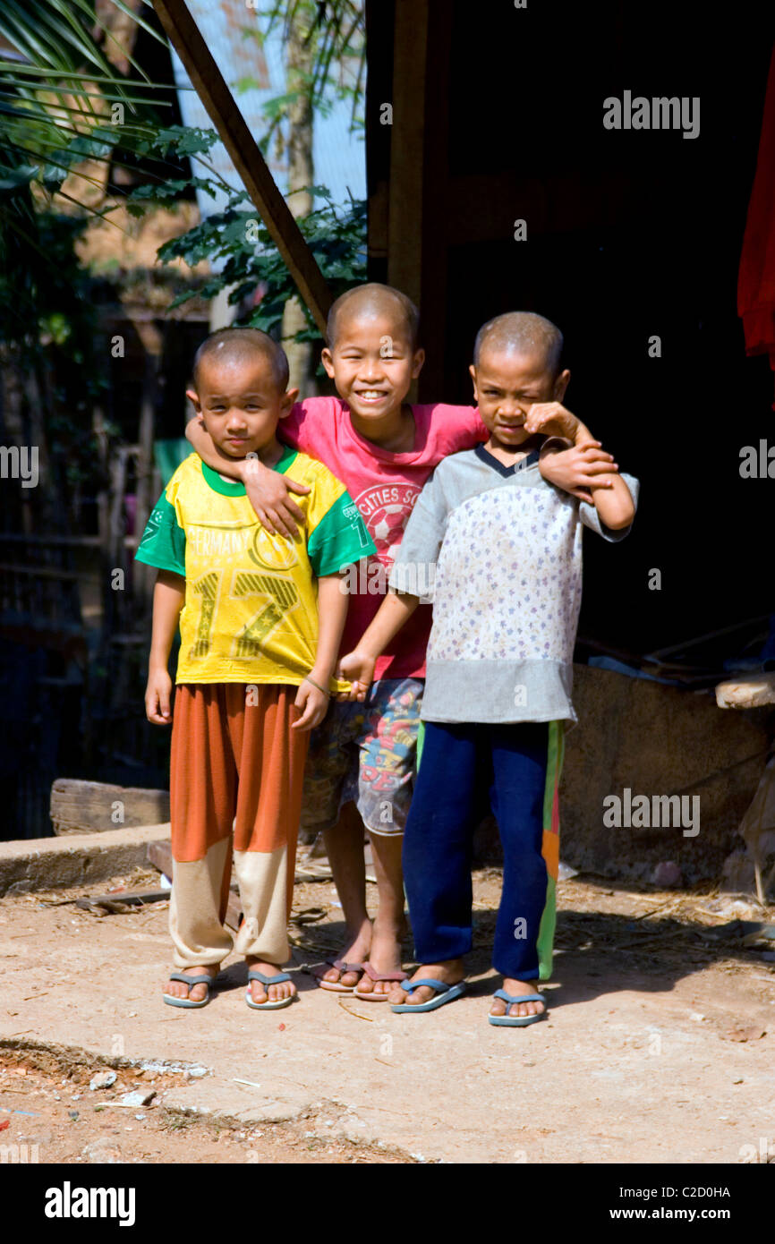 Three young Asian boys living in poverty are standing together at a ...