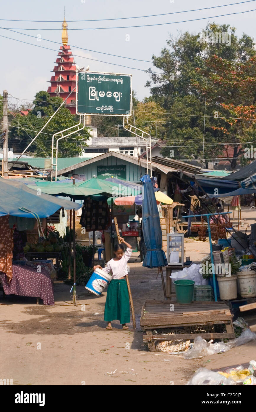 A young girl is carrying a bucket and pole while working in a ...