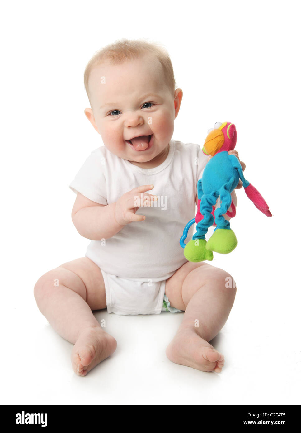 Portrait of an adorable smiling baby playing with a monkey rattle toy ...