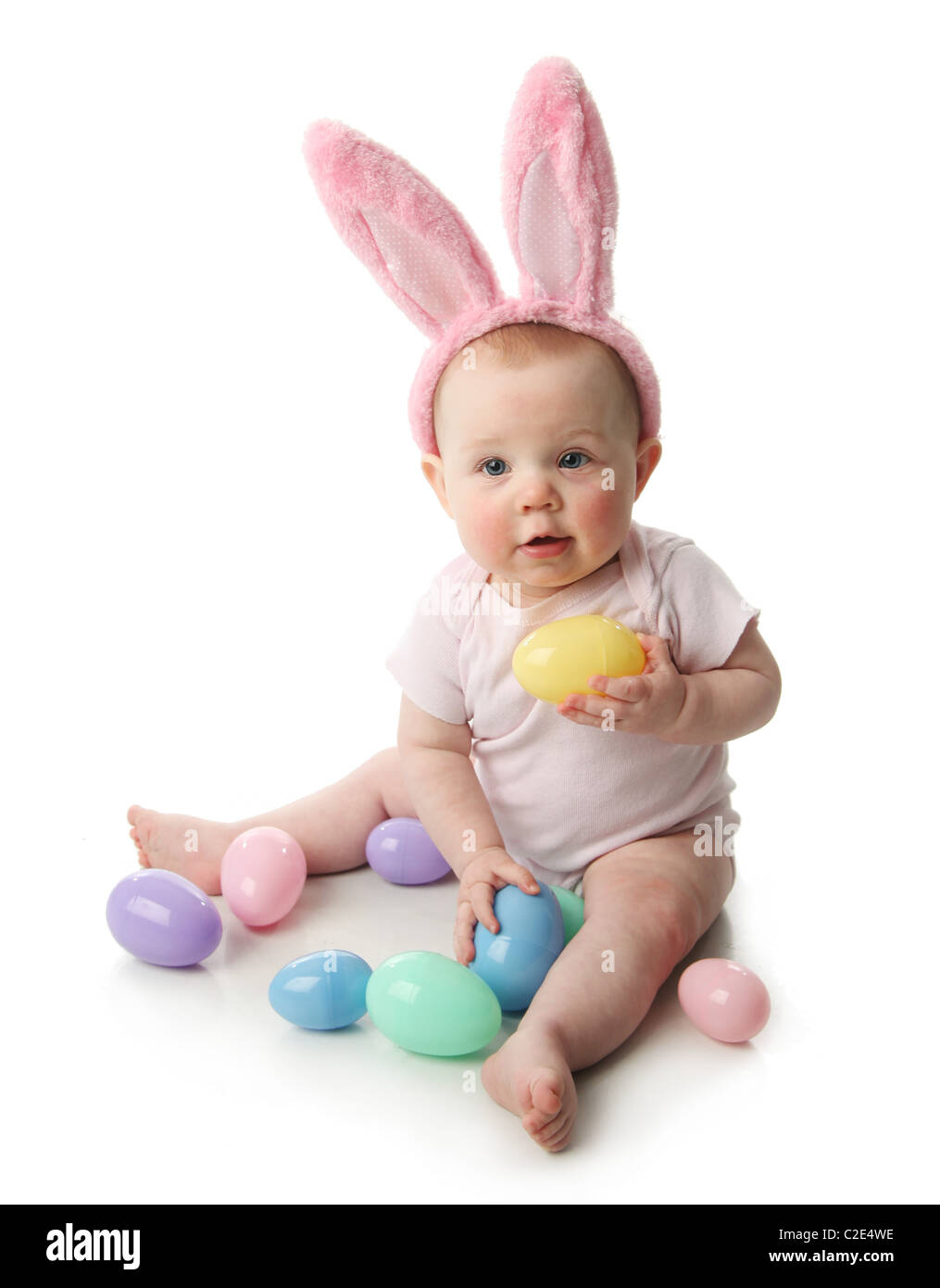 Portrait of a cute baby dressed in Easter bunny ears with pastel eggs ...