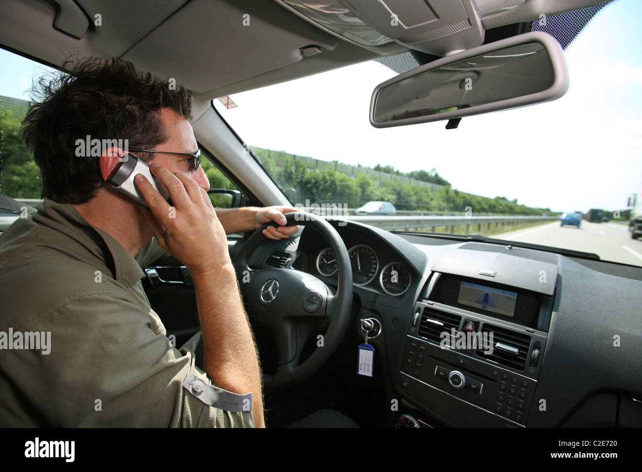 A man using a cell phone without a hands-free device while driving ...