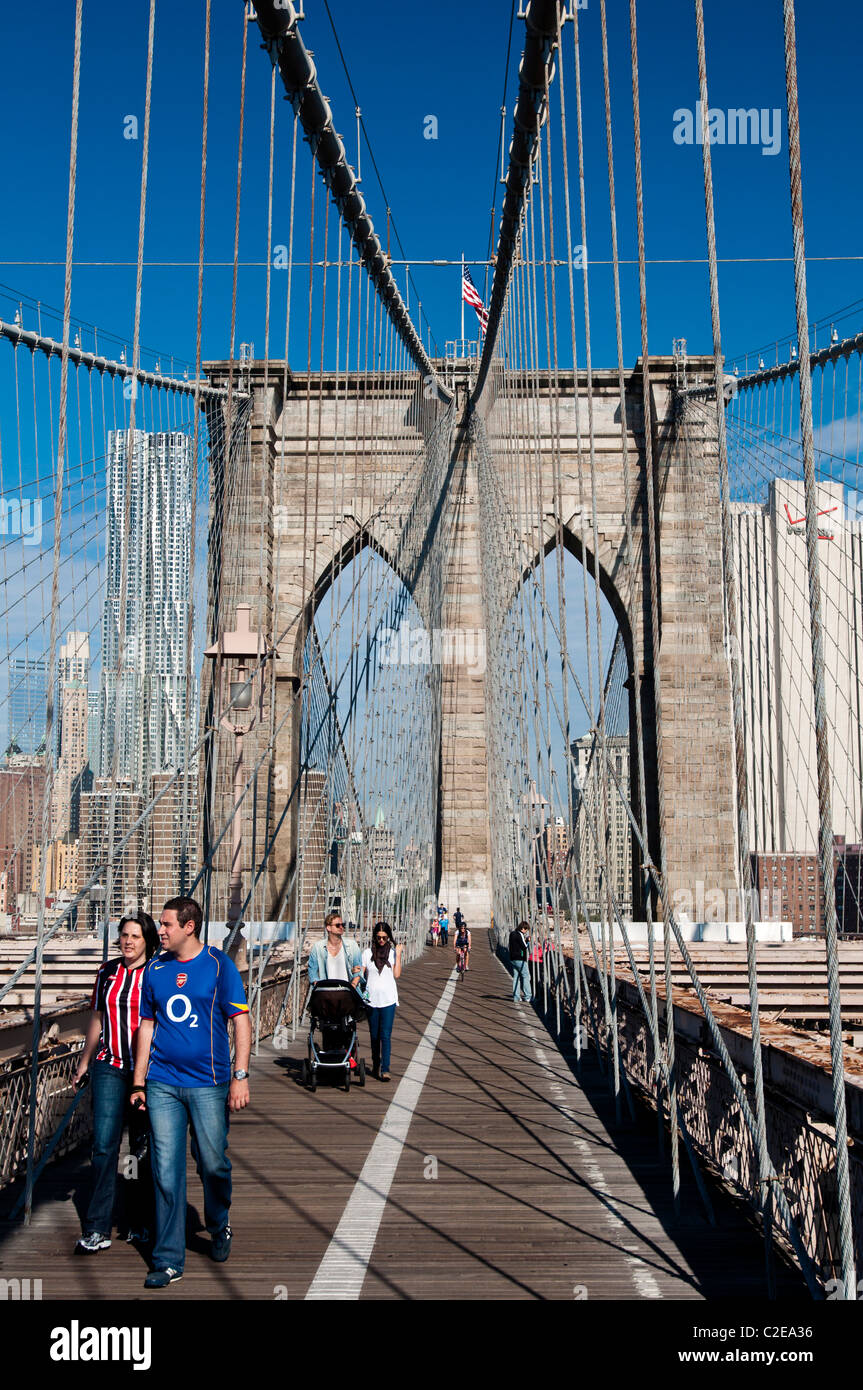 Pedestrians and Brooklyn Bridge Manhattan side tower and web-like cable ...