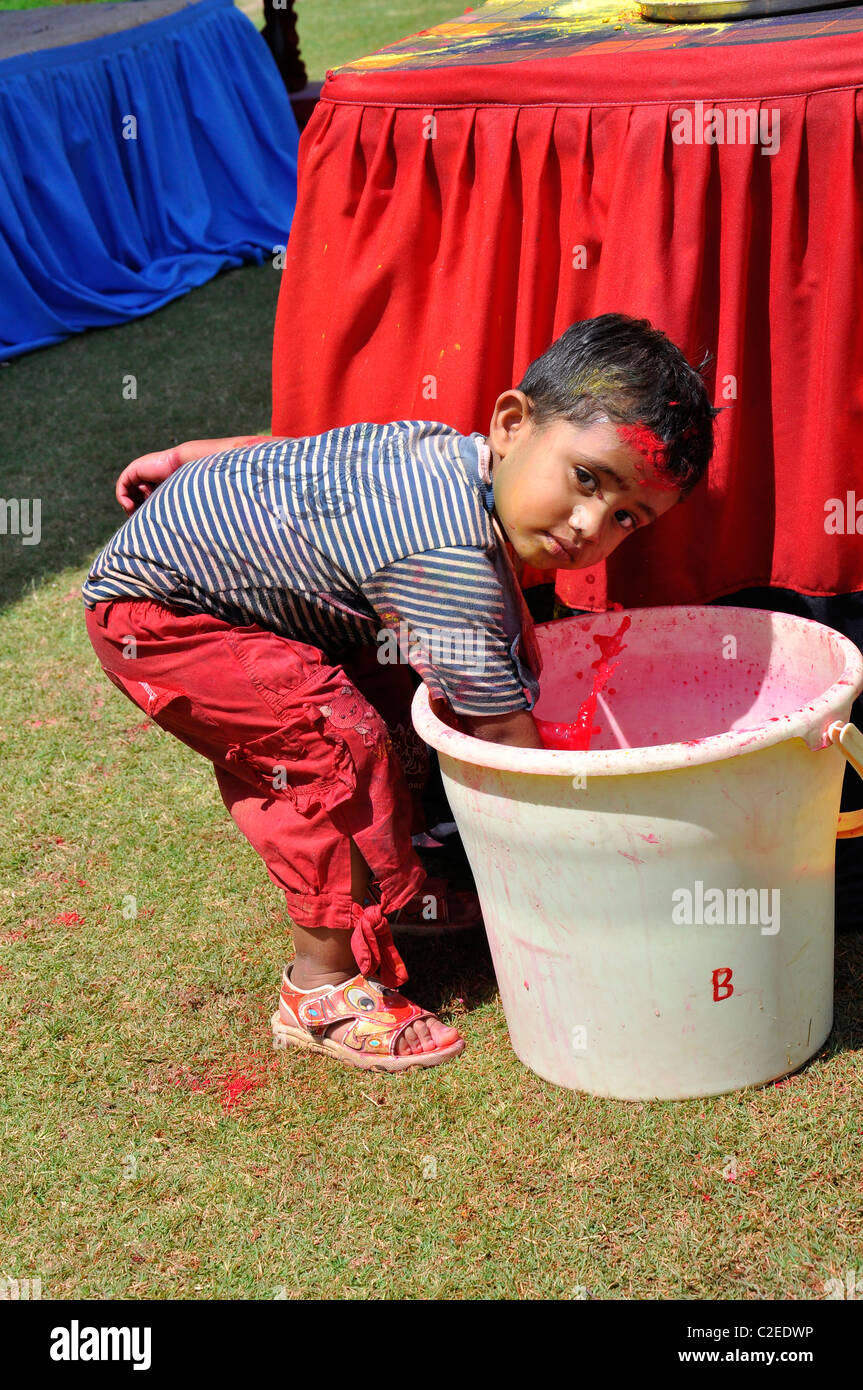 A boy putting hand in a bucket full of colour water on the eve of Holi ...