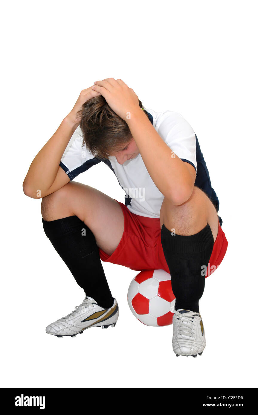 Young and defeated football player seated in a ball isolated in white ...