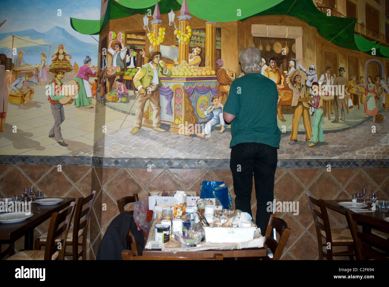 Artist painting mural on the wall of an Italian restaurant Notting Hill ...