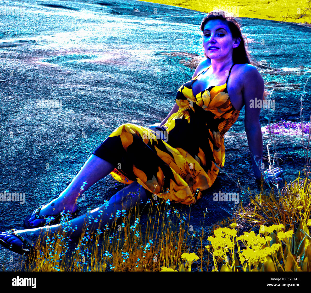 Lovely woman in yellow dress sitting on stone with flowers in the ...