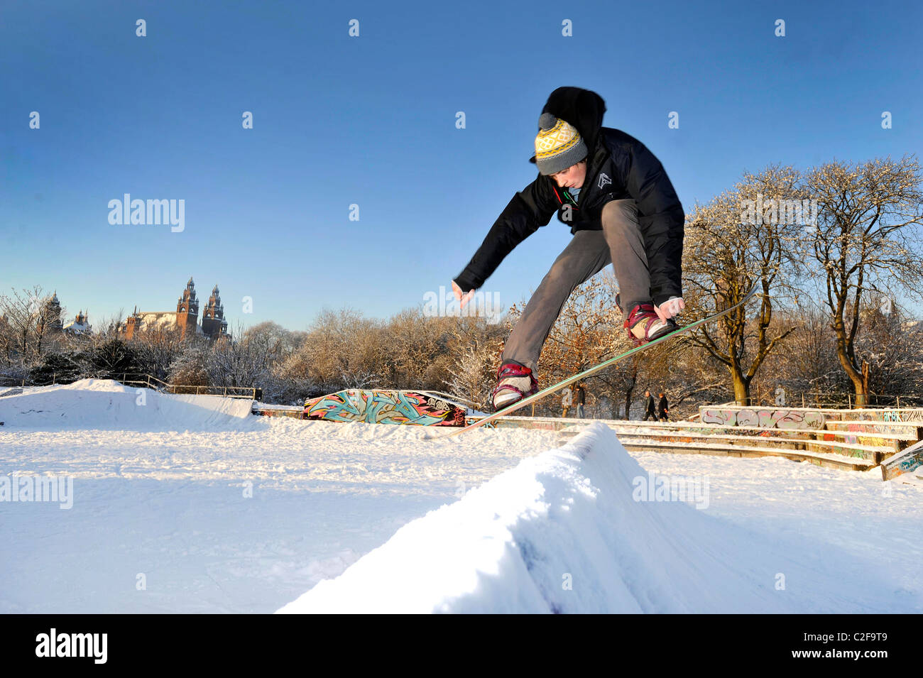 A man rides a snowboard on a snow covered skatepark in Kelvingrove Park ...