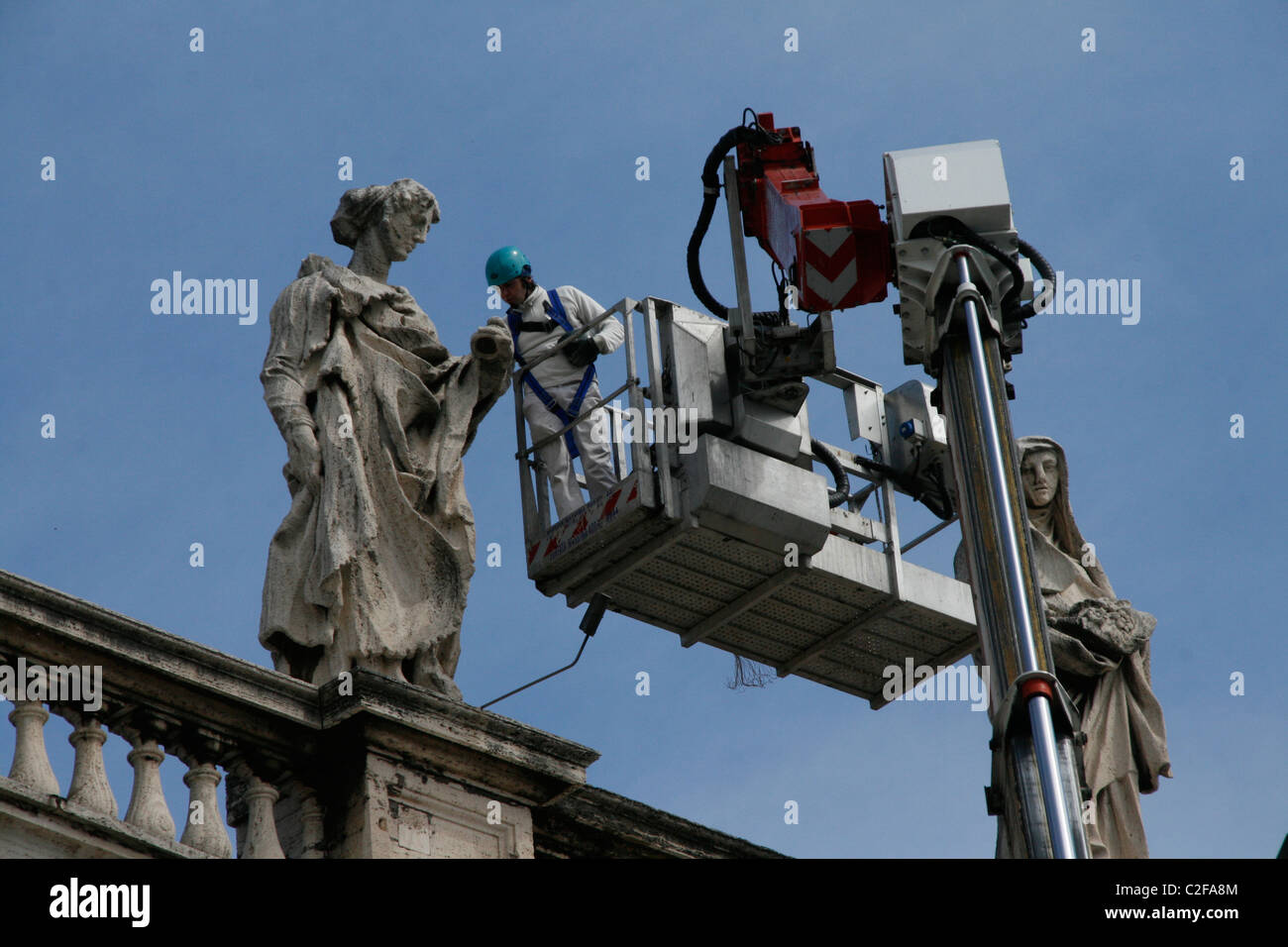 workers repairing statues on top of colonnade at st peter's square in ...