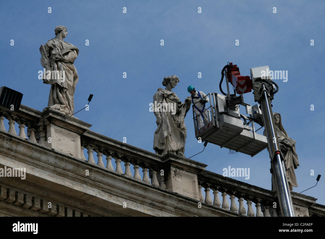 workers repairing statues on top of colonnade at st peter's square in ...