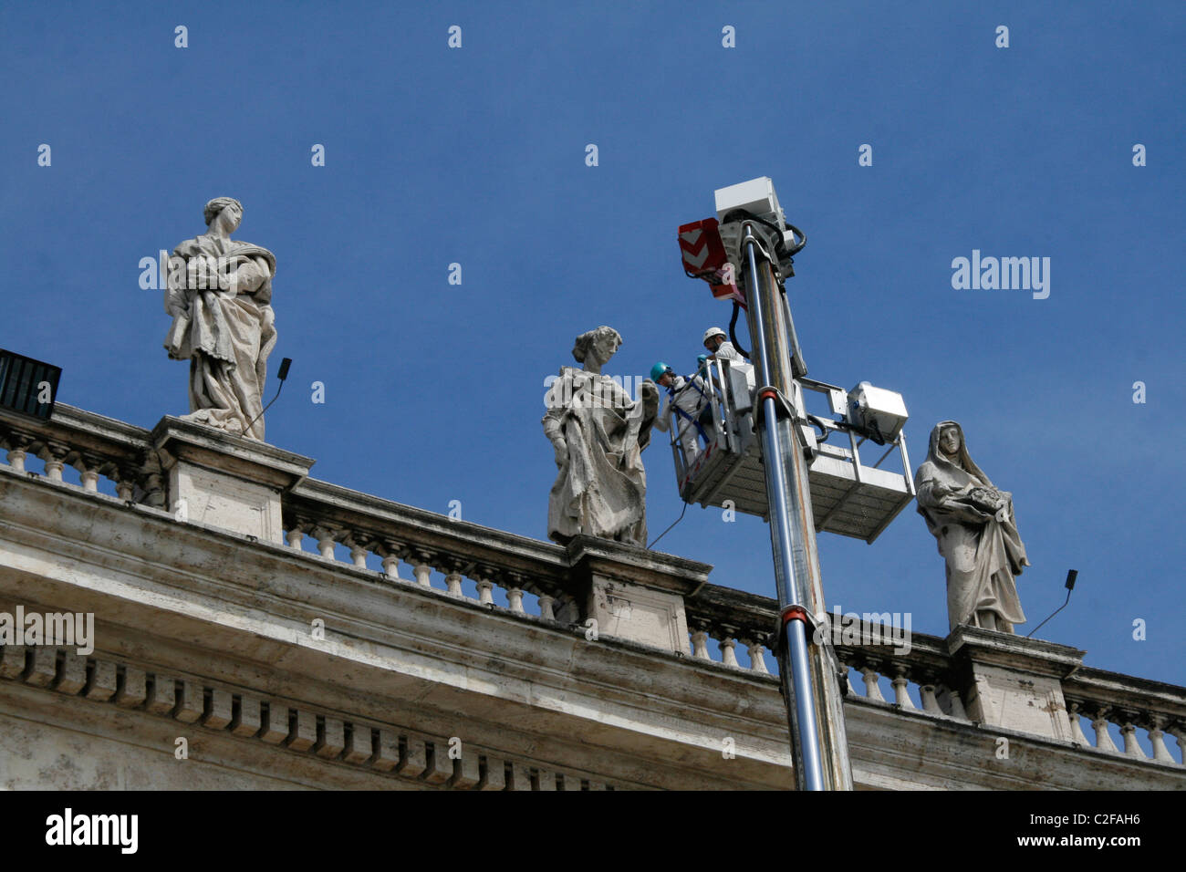 workers repairing statues on top of colonnade at st peter's square in ...