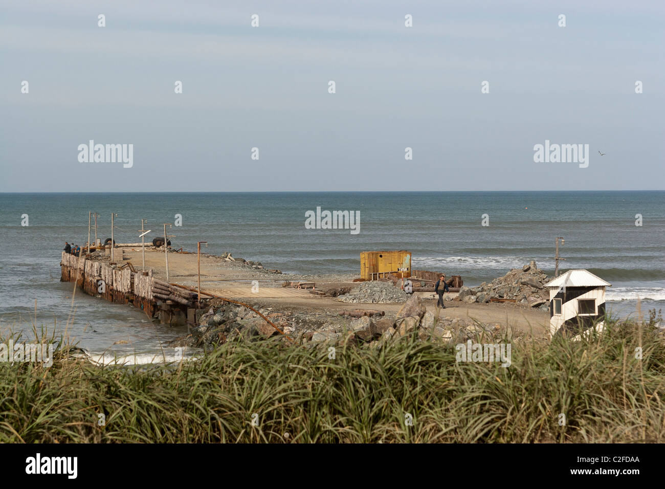 People fish off a pier along the beach in Okhotsk, Sakhalin, Russia ...