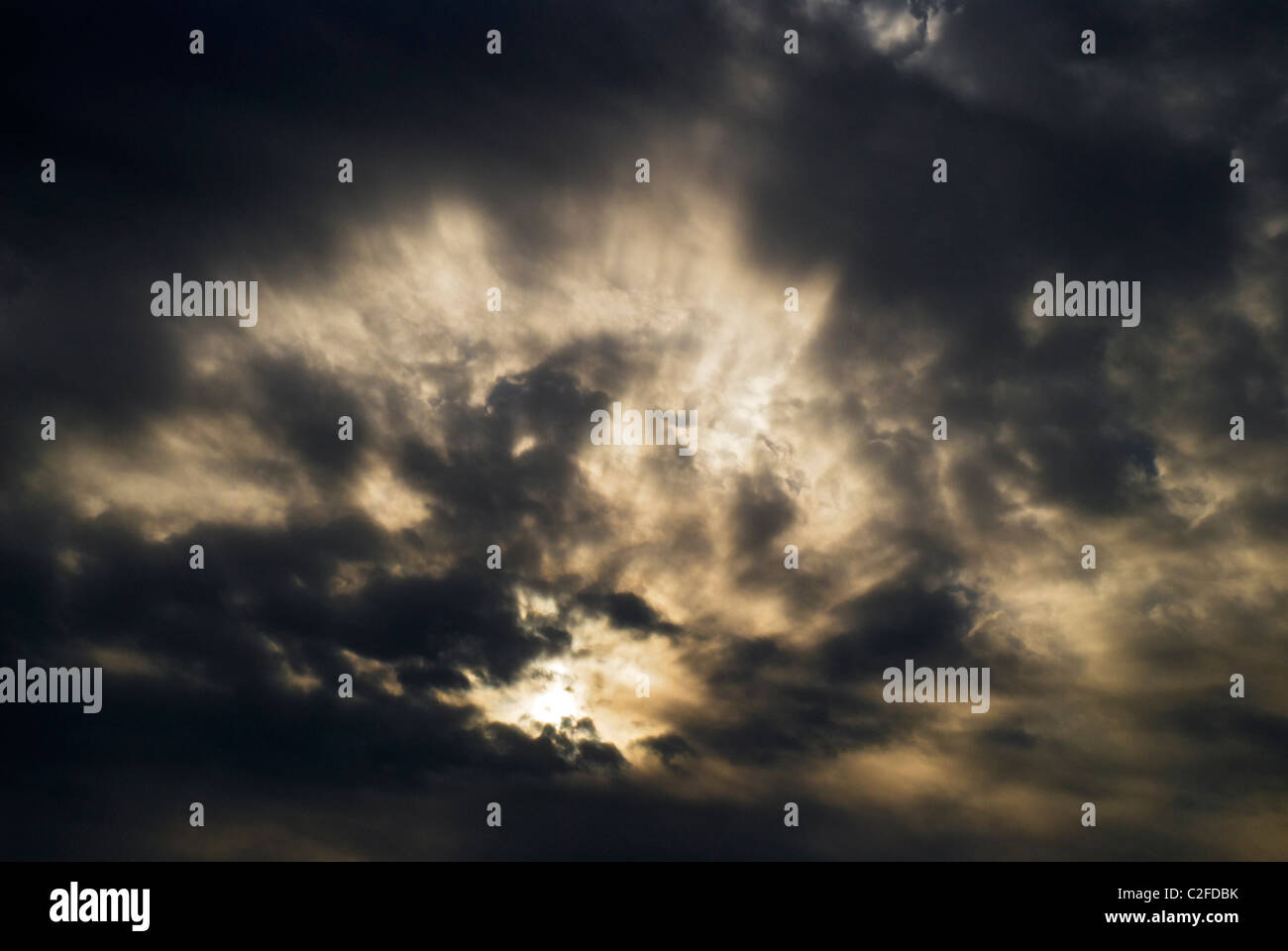 setting sun through dark cloudy sky Stock Photo - Alamy