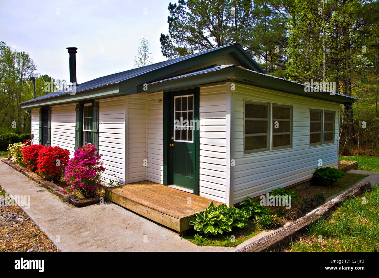 Back view of a cute small farmhouse in the spring with azaleas blooming ...
