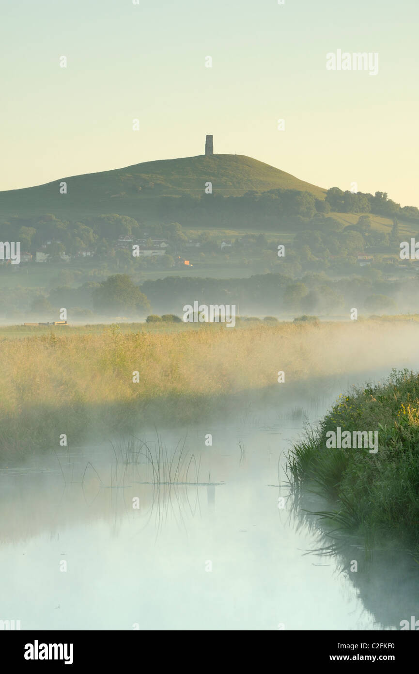 The River Brue with Glastonbury Tor in the distance during a misty ...