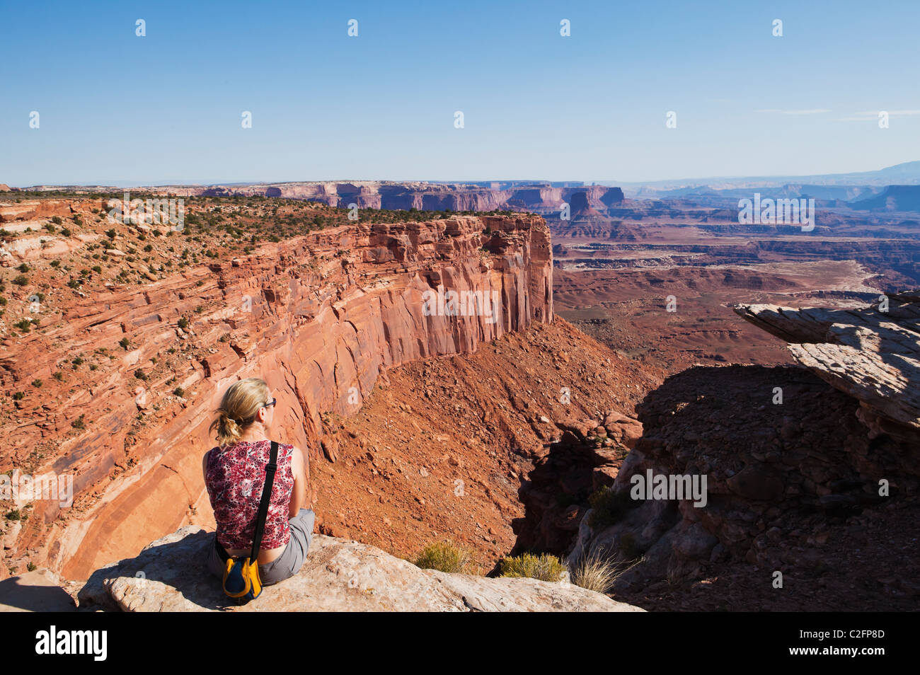 A woman sits atop a cliff in Canyon lands National Park, Utah (Island ...