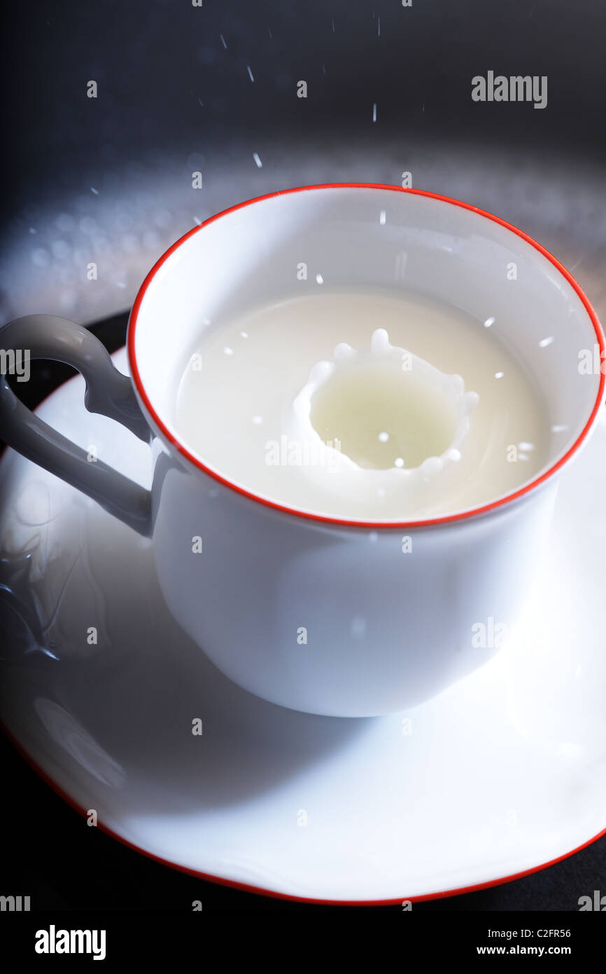 milk drops - milk drop into small cup with milk Stock Photo - Alamy