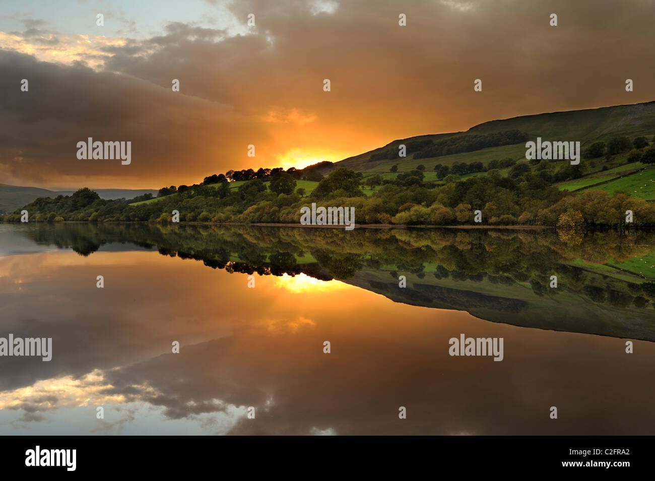 A fiery autumn sunset reflected in the still waters of Semer Water ...