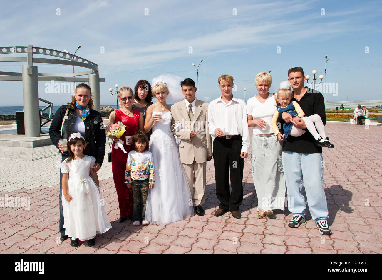 A wedding party poses for a photo on the waterfront in Kholmsk ...