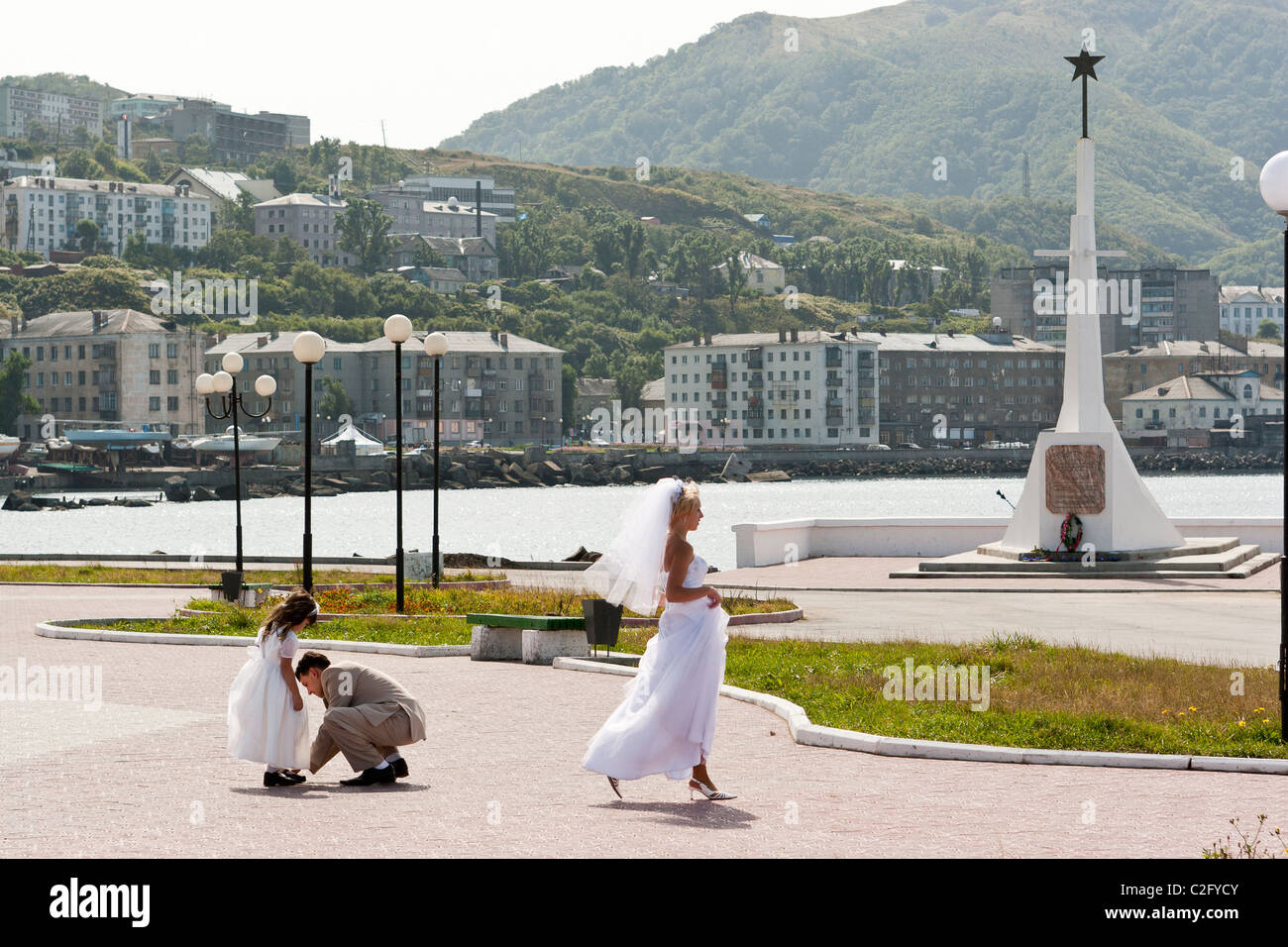 Members of a wedding party and the bride walk along the waterfront in ...
