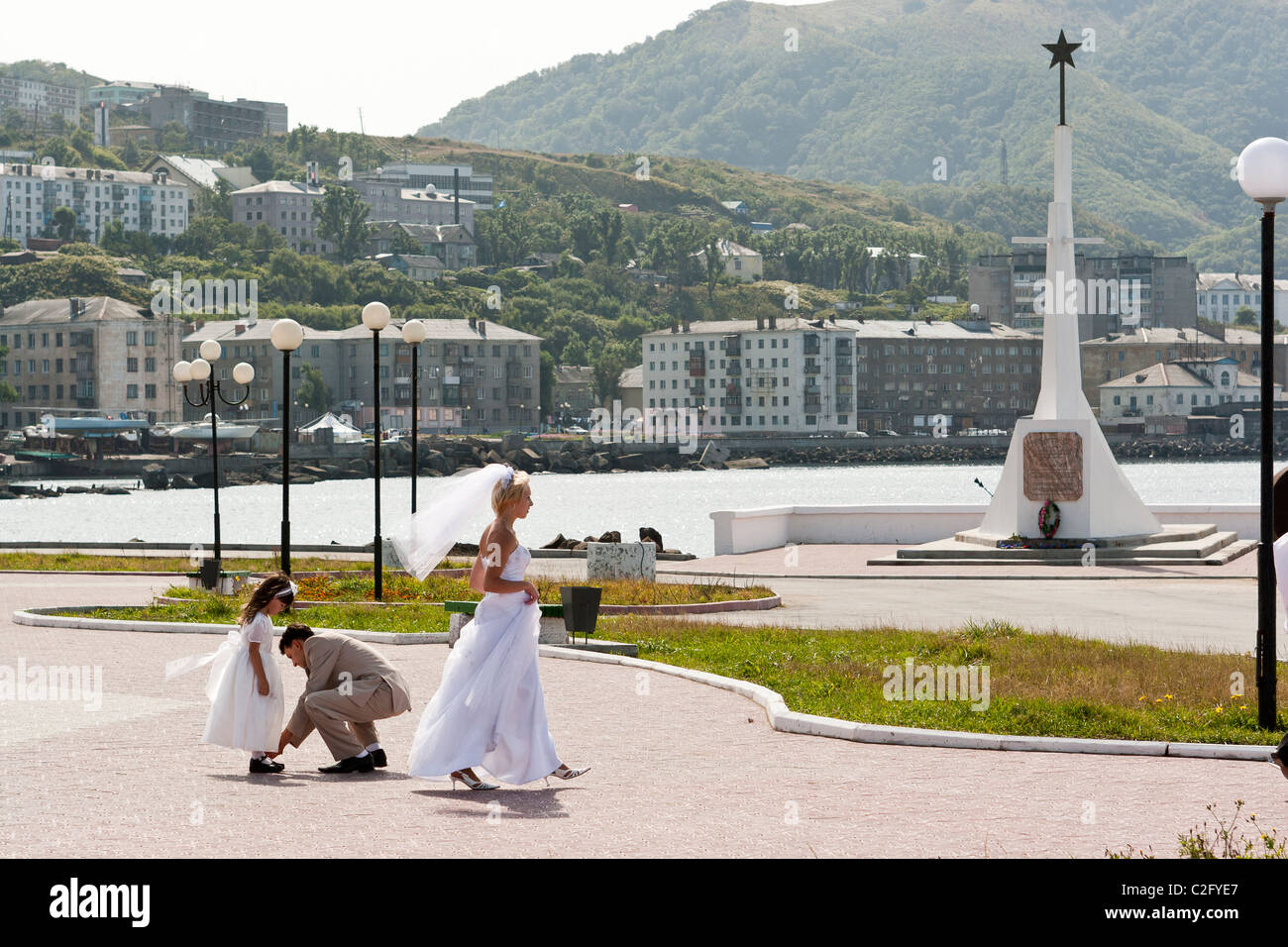 Members of a wedding party and the bride walk along the waterfront in ...
