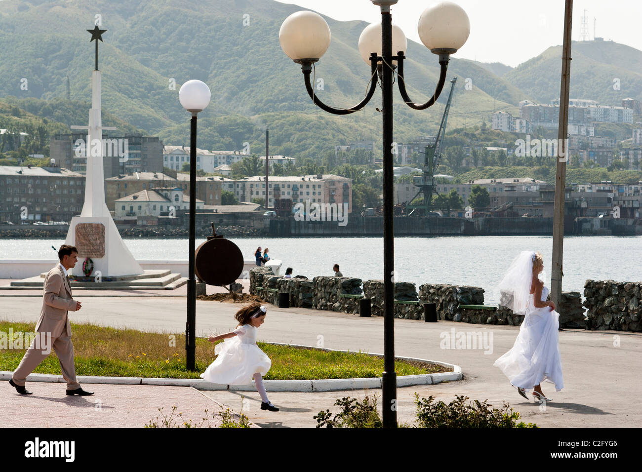 Members of a wedding party and the bride walk along the waterfront in ...
