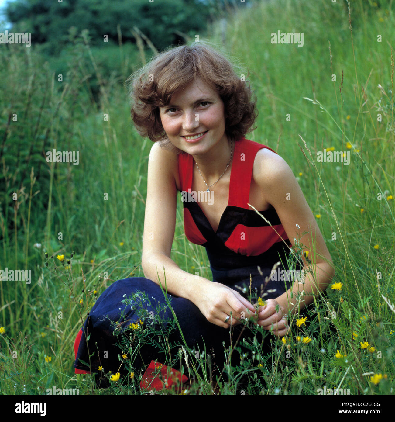 Siebziger Jahre, Menschen, junge Frau hockt im Gras, Portraet ...