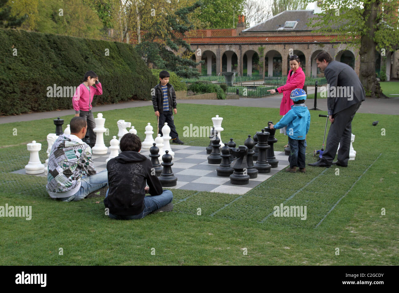 UK. FAMILIES PLAYING WITH GIANT CHESS BOARD IN HOLLAND PARK IN LONDON ...
