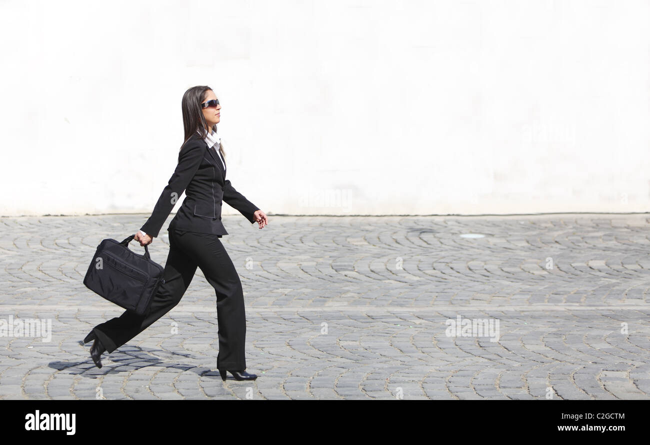 Young businesswoman walking along a cobbled street in front of a white ...