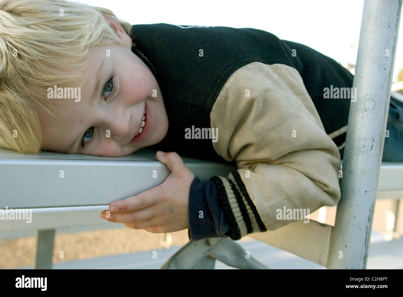A 6 year old boy resting on a bench at his school in Alameda, CA Stock ...