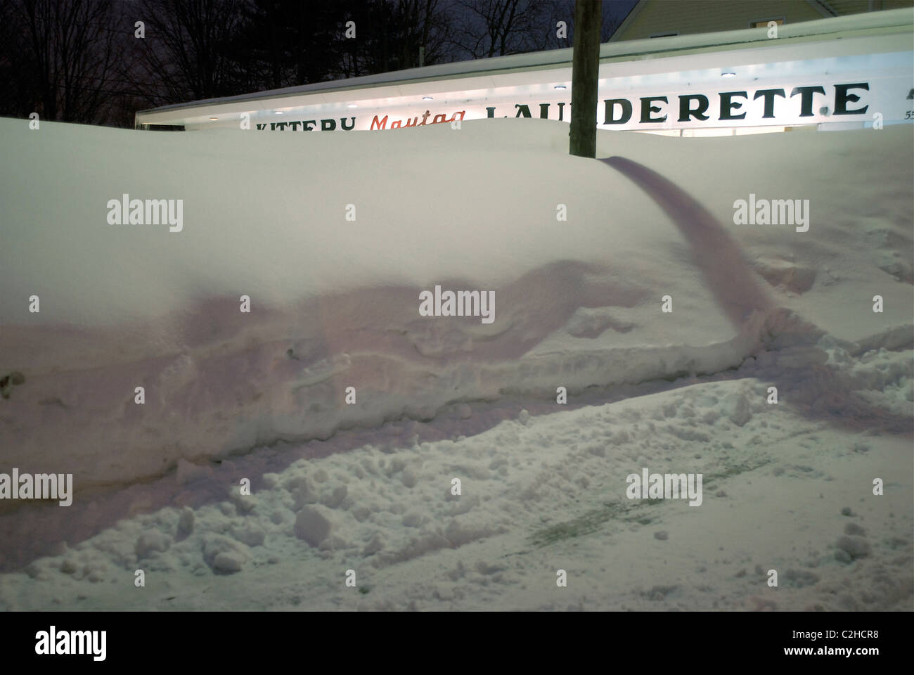 Snow bank piled high in front of launderette at night Stock Photo - Alamy